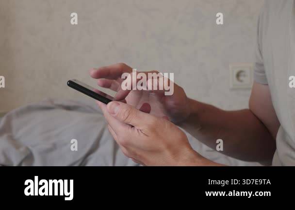 A mans hand taps on a smartphone screen, a person interacting with a personal mobile device ...
