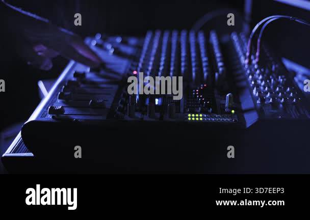 Wide angle of a sound engineer adjusting faders on an audio mixer with ...