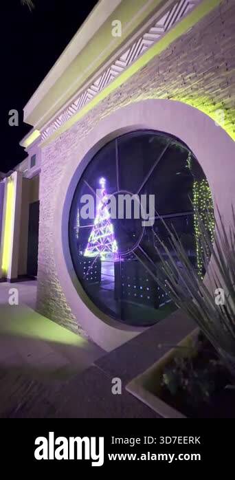 Round window with neon reflection of Christmas tree with star at night ...