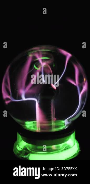 Angled plasma globe pink green bolts from central electrode. Glass ...