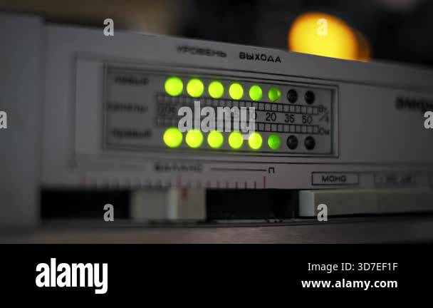 Angled close-up of a vintage stereo amplifier with a pulsing LED meter ...