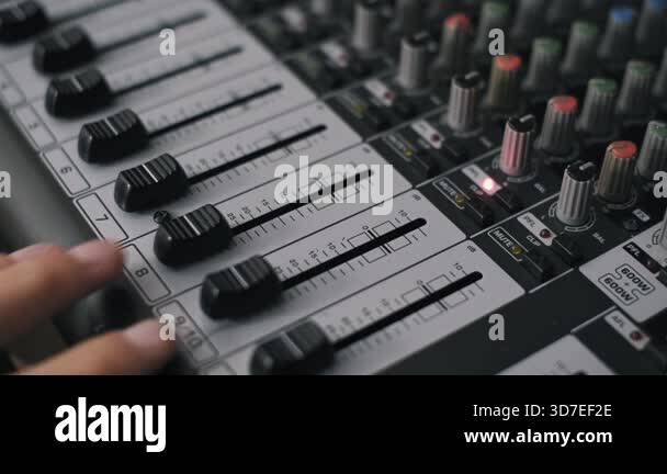 High angle close-up of a sound engineer hand pushing two channel faders ...