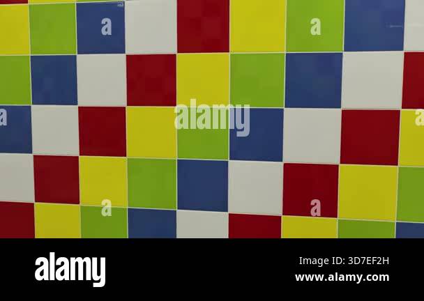 Angled view of a wall covered in colorful square ceramic tiles. Red ...