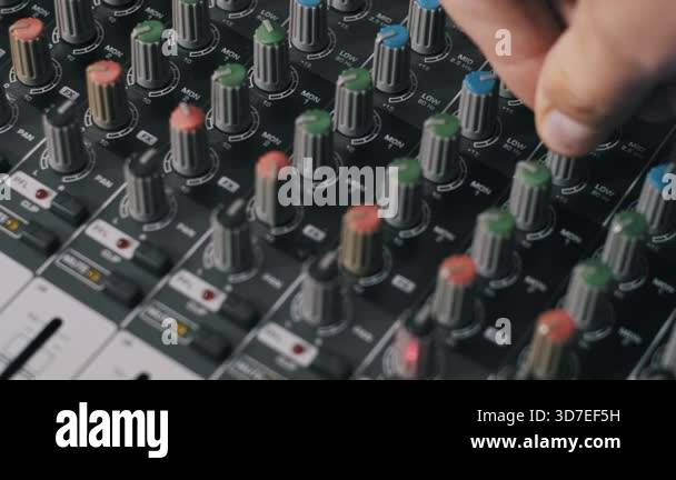 Close-up high-angle of a sound engineer hand turning color-coded knobs ...