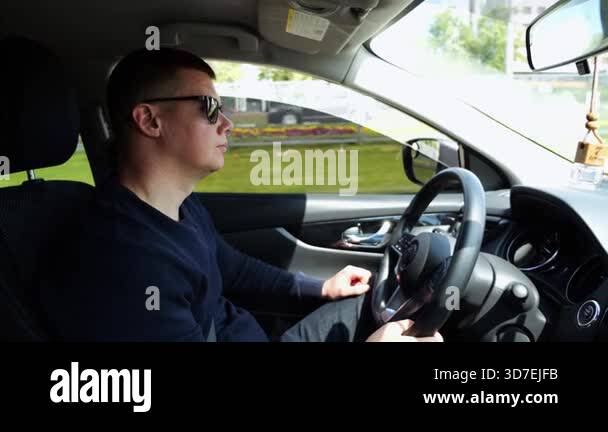 Serious male driver in sunglasses looking concentrated to urban road ...