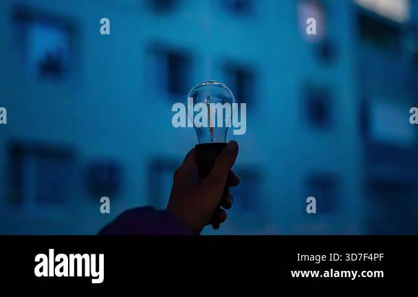 A lamp without light in a hand against the background of a multi-story building in the evening ...