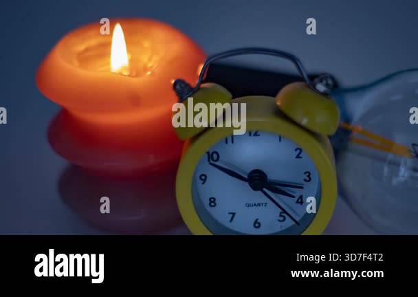A burning candle, a light bulb, and an alarm clock. Power outages due ...