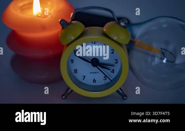 A burning candle, a light bulb, and an alarm clock. Power outages due ...