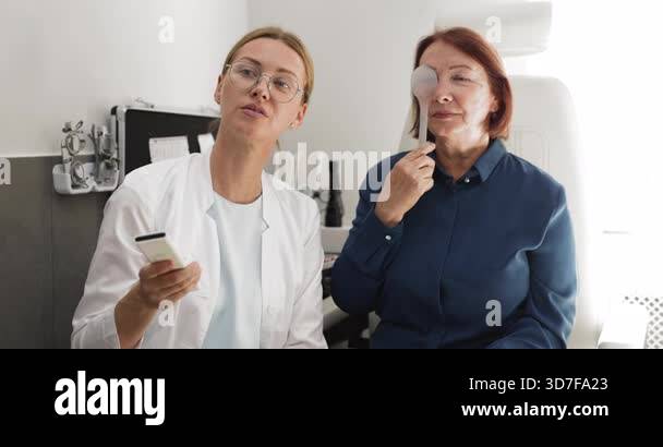 Optometrist conducting visual acuity test for elderly woman in ...