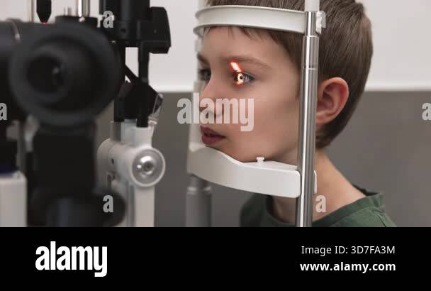 Cute school-age 8s boy having eye checkup with slit lamp microscope ...