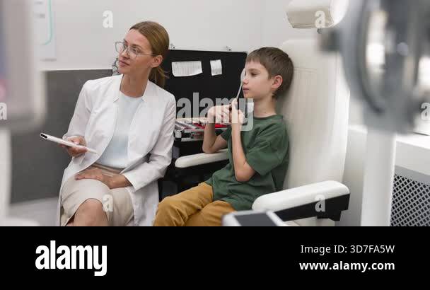 School-age boy during vision consultation with female optometrist in ...