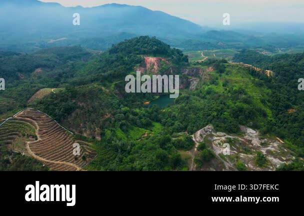 Aerial view of a lush green hill surrounded by rugged cliffs and a ...