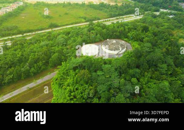 Aerial view of water storage tanks surrounded by dense green forest ...