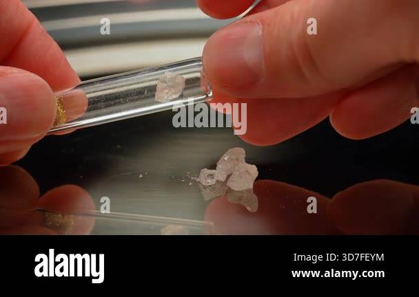 Placing crystals of drug in glass smoking pipe from harm reduction stem ...