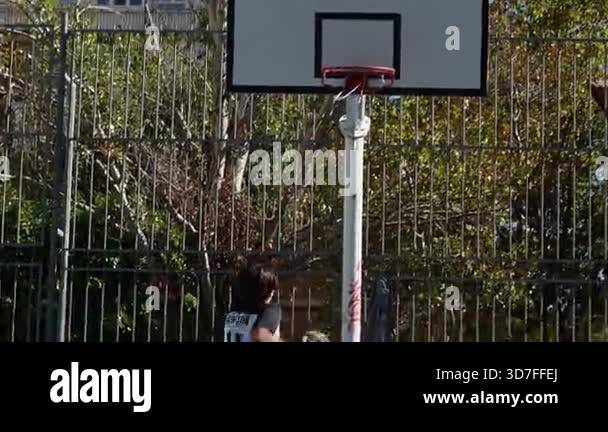Athletic man shooting a basketball and making a hoop on a sunny day in ...