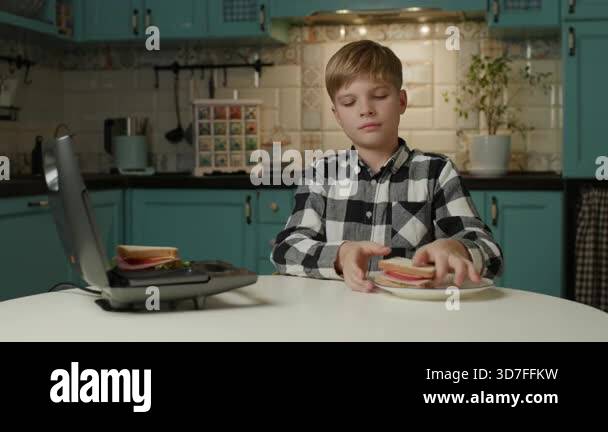 Young boy preparing a sandwich in a sandwich maker at home, enjoying a ...