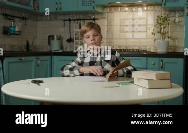 Young boy sitting at home writing in a notebook, possibly doing ...