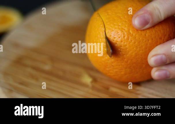 Close up of female hand cutting a fish orange fruit on wooden cutting ...