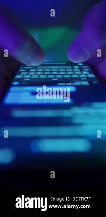 Close-up of fingers typing text message on smartphone keyboard in dark ...