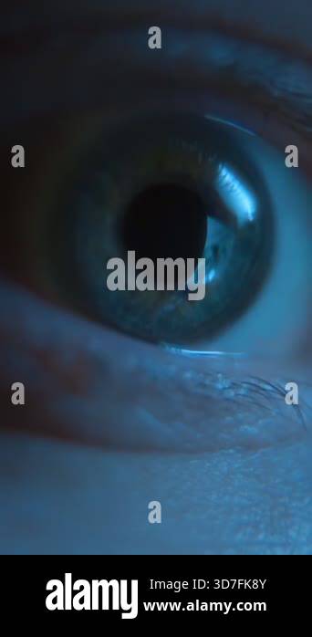Zoom in close up of wide open human eye looking at glowing display with ...