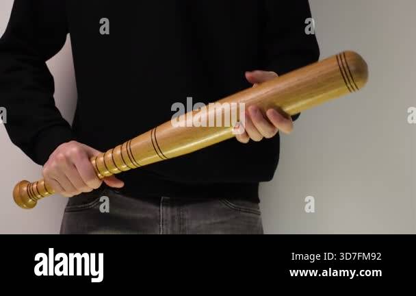 A man holds a baseball bat in his hands and rubs them together close-up ...