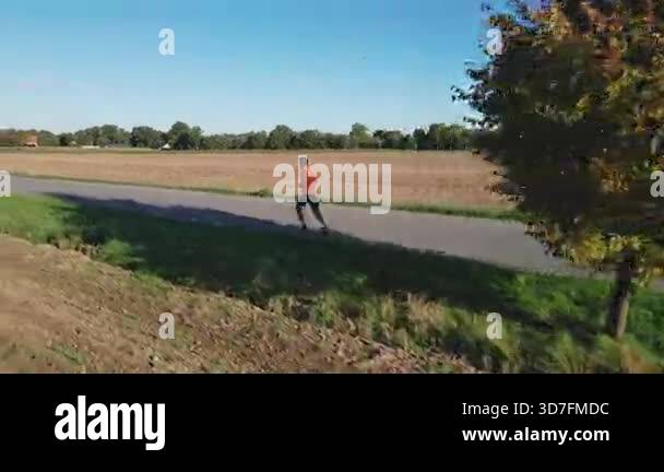 Man jogging on empty country road near agricultural field and green ...