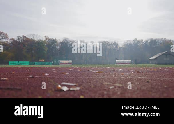 Man doing running drills on track with fallen autumn leaves. Male ...