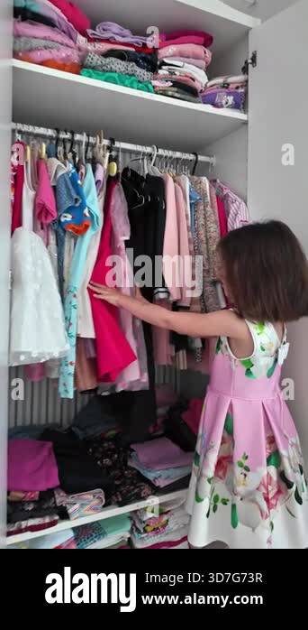 Little girl choosing clothes from the wardrobe. Girl choosing dress a ...
