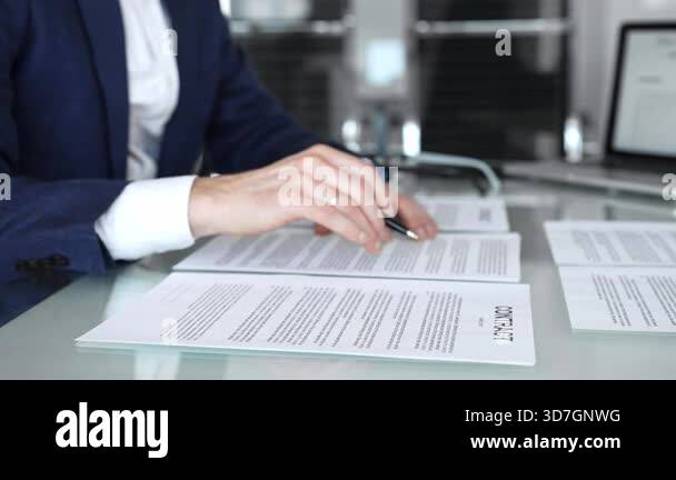 Business professional reviewing and signing a formal contract on a desk ...