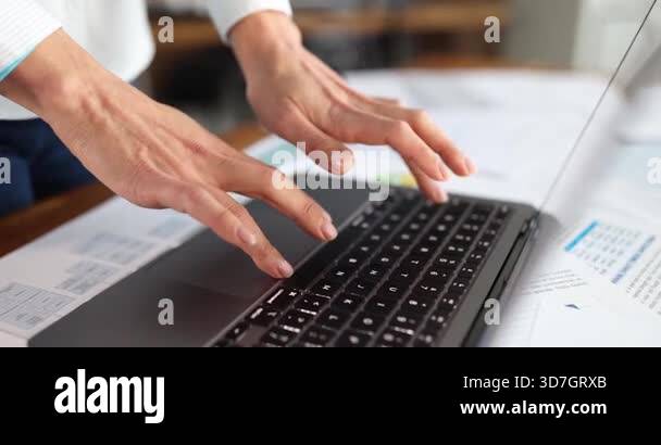 Woman office worker types on modern laptop keyboard focusing carefully ...