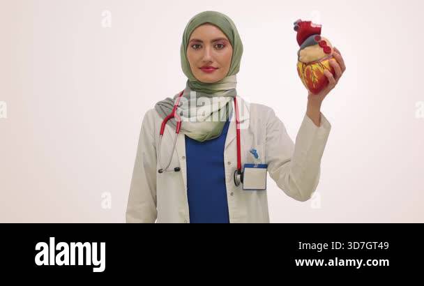 Muslim cardiologist holds anatomical model of heart and blister pack of ...