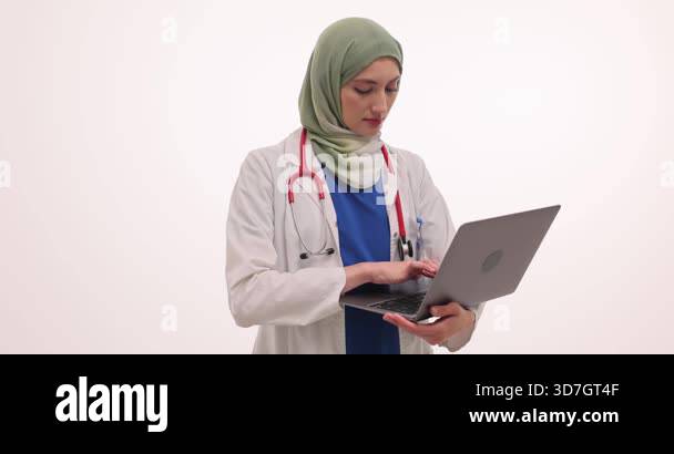 Woman doctor types on laptop reviewing patient data analysis. Muslim ...