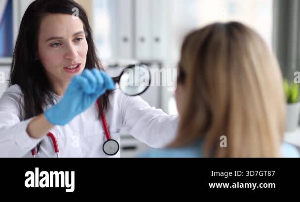 Woman doctor holds magnifier glass examining face skin of woman patient ...