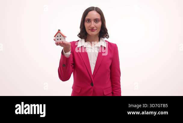 Woman agent in red suit stands in studio holding house model with ...