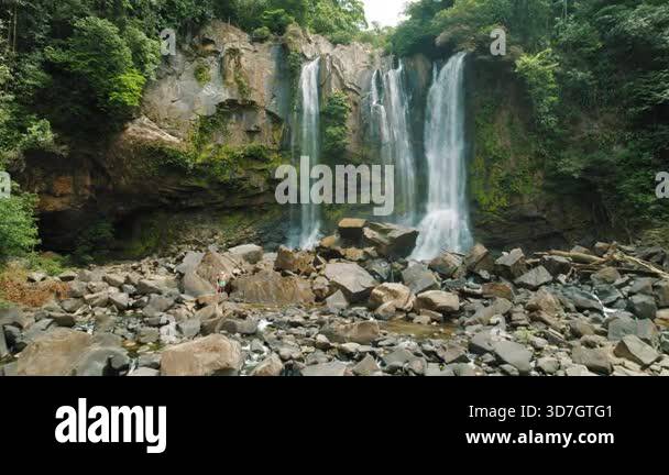Travelers explore the massive Nauyaca Waterfalls by lush jungle cliff ...