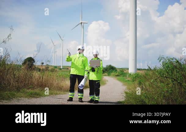 Engineers wearing safety helmets inspecting a wind turbine at a wind ...