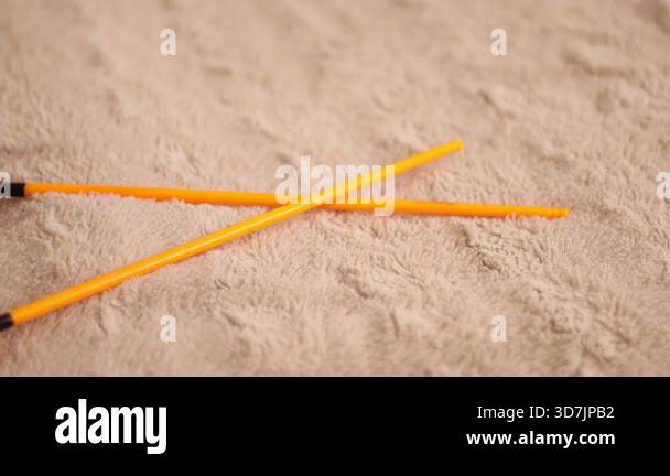 Two bright orange plastic sticks are tapped together, producing a ...
