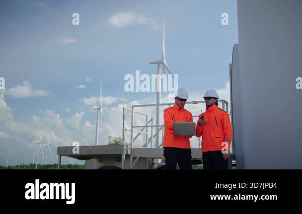 Engineers wearing safety helmets inspecting a wind turbine at a wind ...