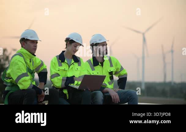 Team of engineers wearing safety helmets inspecting wind turbines at a ...