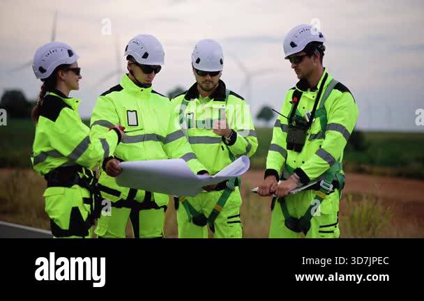 Engineers wearing safety helmets inspecting a wind turbine at a wind ...