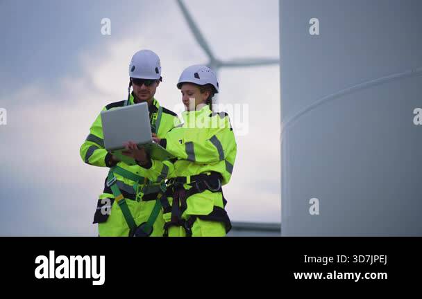 Engineers wearing safety helmets inspecting a wind turbine at a wind ...