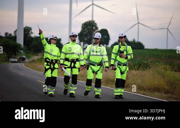 Team of engineers wearing safety helmets inspecting wind turbines at a ...