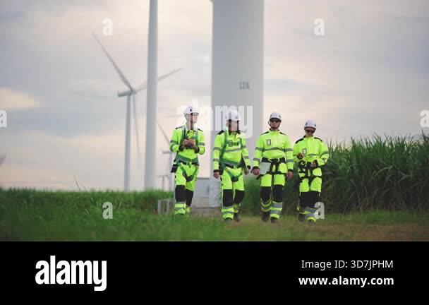 Team of engineers wearing safety helmets inspecting wind turbines at a ...