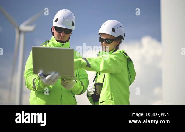 Engineers wearing safety helmets inspecting a wind turbine at a wind ...