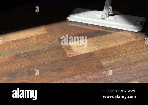 Top view of a flat mop washing a wooden floor with visible detergent ...
