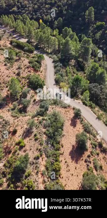 Aerial drone footage of a car driving along a winding rural road ...