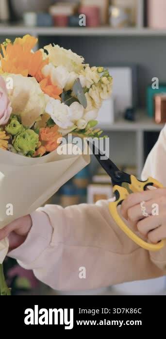 Caucasian woman florist cuts beautiful flowers with scissors before ...