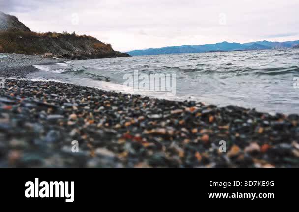 Low-angle shore break on pebble beach in cloudy weather. High quality ...