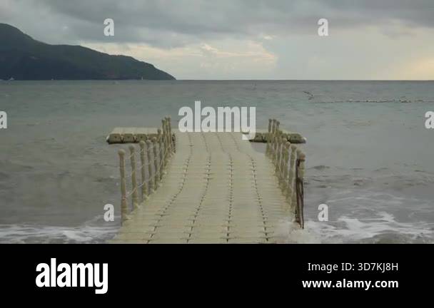 Floating plastic dock on a wavy sea during a rainy day. The unstable ...