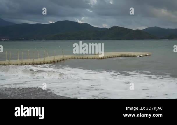 Floating plastic dock on a wavy sea during a rainy day. The unstable ...
